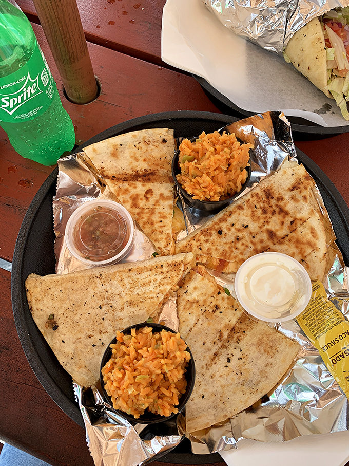A quesadilla cut with geometric precision, surrounded by dipping options that suggest someone in the kitchen understands the importance of sauce architecture. 