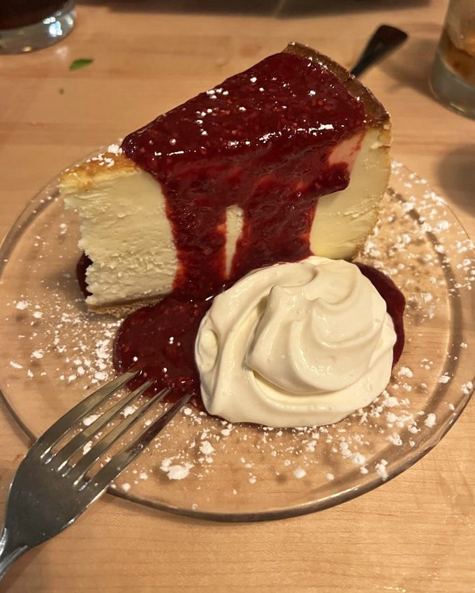 Cheesecake topped with raspberry sauce that makes diets disappear faster than magic tricks. Worth every delicious calorie and momentary guilt.
