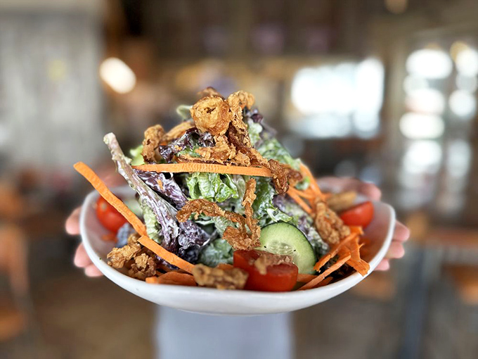 This salad towers like a skyscraper of freshness, proving vegetables can party just as hard as those fries.