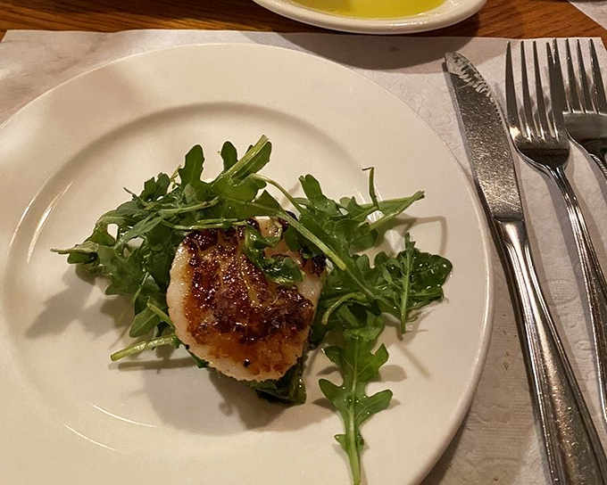 A perfectly seared scallop perched atop peppery arugula &ndash; proof that restraint can sometimes deliver the most powerful flavors.