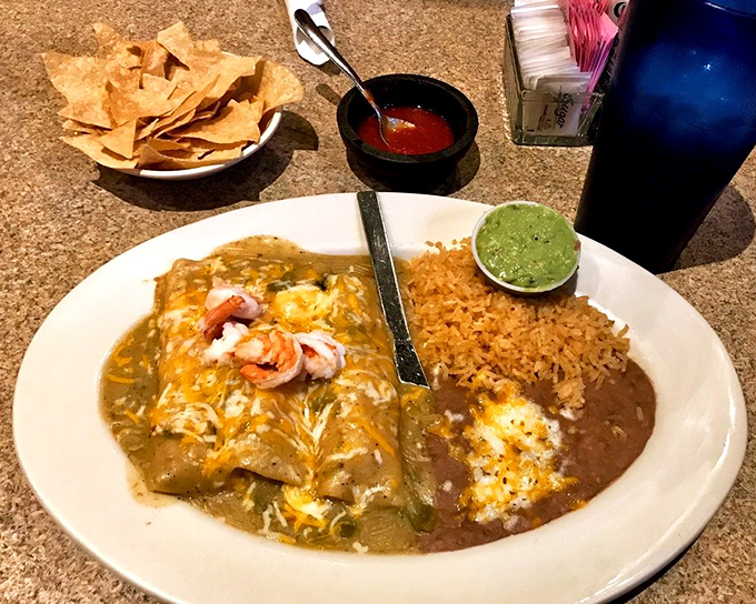 Shrimp enchiladas draped in green sauce with rice and beans—a plate that makes you wonder why you'd ever order anything else.