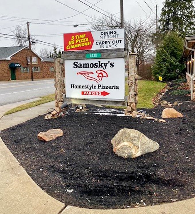 The sign says it all: champions of pizza, masters of hospitality. This stone marker has guided hungry travelers for years.