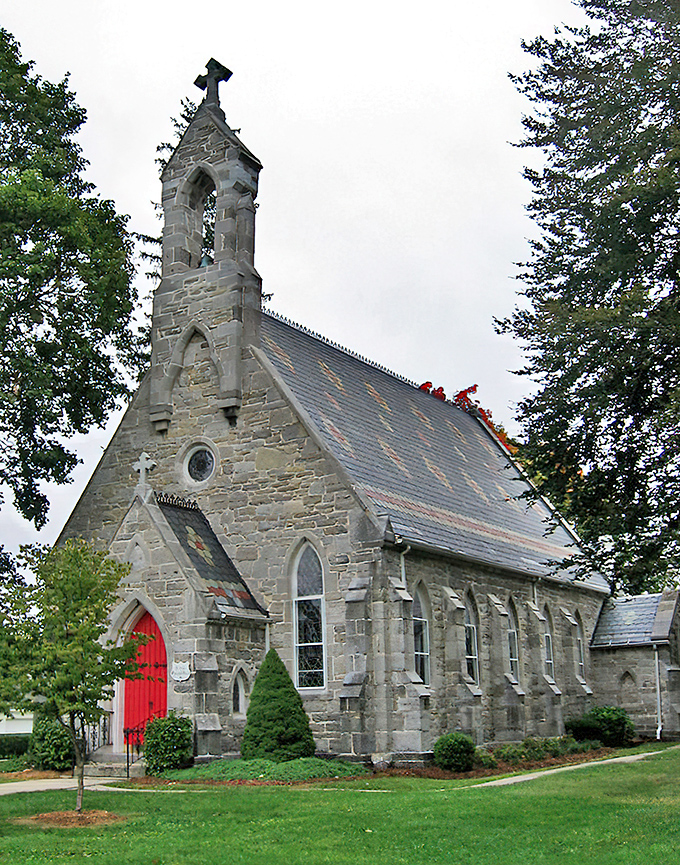 This stone church reaches skyward with Gothic grace, its red door welcoming souls like a beacon of hope.