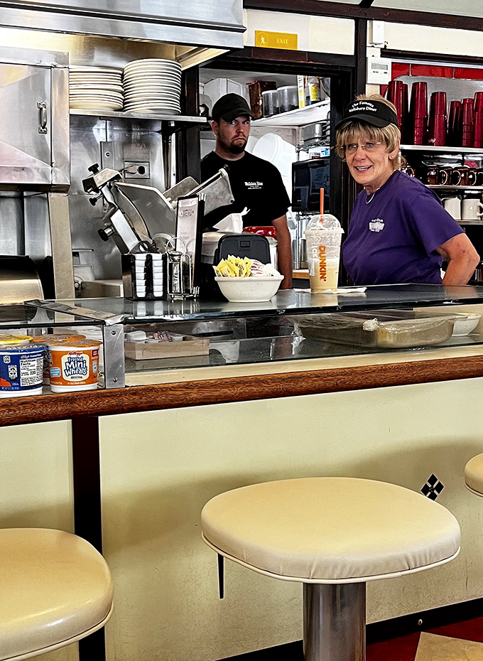 The unsung heroes behind the counter, working their magic in a kitchen smaller than most walk-in closets. Their efficiency is a choreographed dance of comfort food creation.