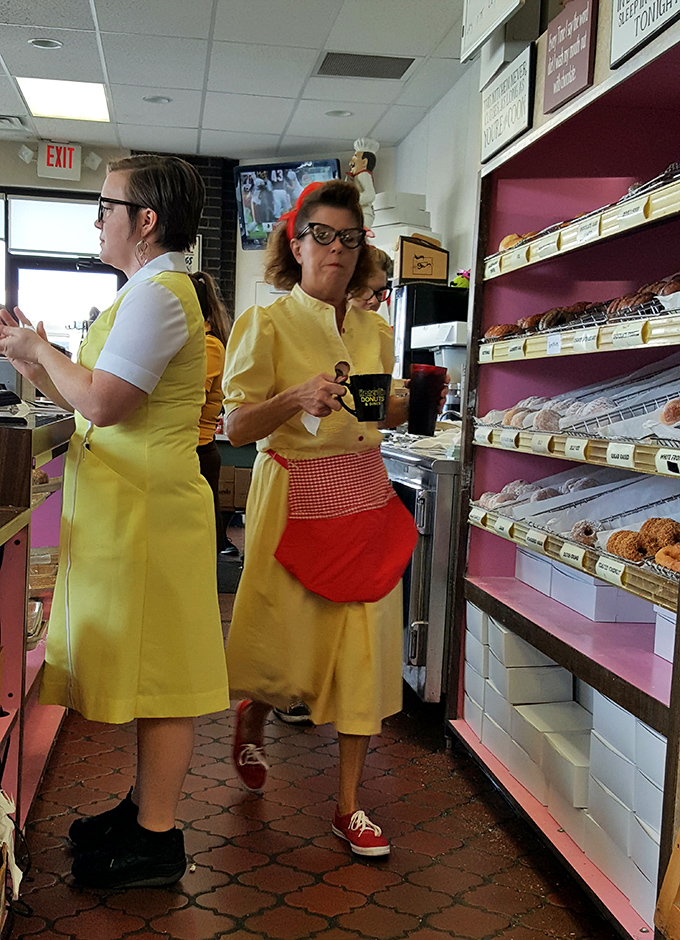 The yellow-aproned guardians of the donut galaxy, working their morning magic with the efficiency of seasoned breakfast professionals.