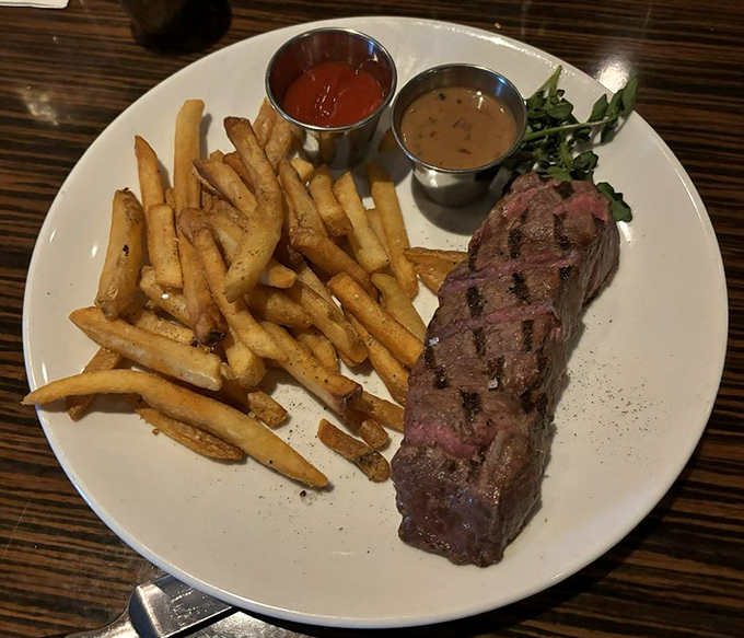 Steak frites that speak fluent delicious. The medium-rare strip lounges confidently beside golden fries, with sauces standing by for dipping duty.
