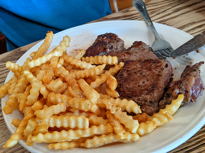 A properly cooked steak alongside crispy waffle fries – proof that sometimes the simplest pleasures are the most satisfying.