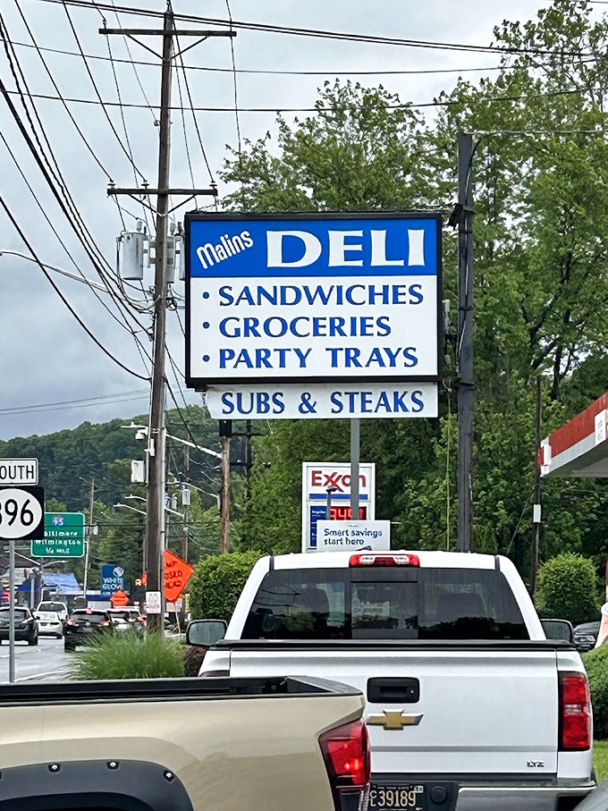 The roadside sign stands as a beacon of hope for the hungry traveler&mdash;SANDWICHES, GROCERIES, PARTY TRAYS&mdash;three promises worth pulling over for.