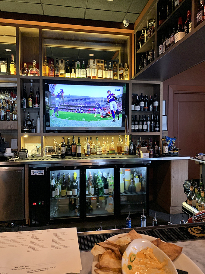 The bar area&mdash;where bourbon bottles stand at attention and sports play on TV, creating that perfect "fancy but you can still watch the game" vibe.
