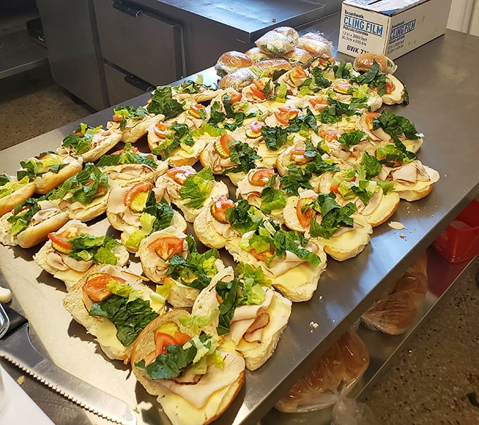 The assembly line of open-faced subs awaiting completion showcases the fresh ingredients and attention to detail that elevate Mickey's above ordinary sandwich shops.