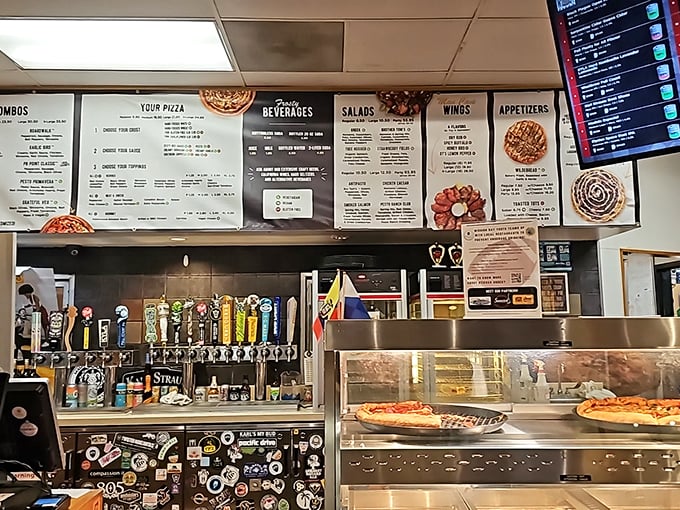Where pizza dreams begin – the counter view revealing tap handles and pizza by the slice, a siren song for the hungry passerby.