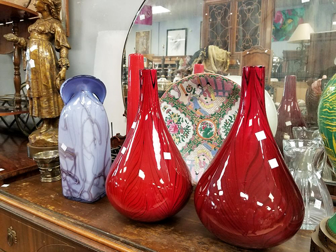 Those red glass vases aren't just decorative &ndash; they're statement pieces that transform a boring shelf into an art installation.