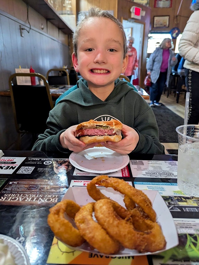The image shows a young diner enjoying what appears to be the famous bologna sandwich with a side of onion rings &ndash; creating food memories that will last a lifetime.