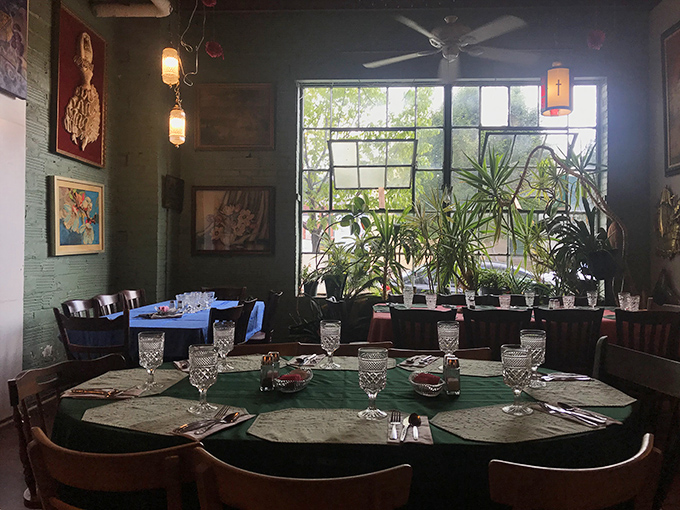 Sunlight streams through plants creating nature's stained glass, while crystal glasses await. Dining here feels both grand and utterly unpretentious.