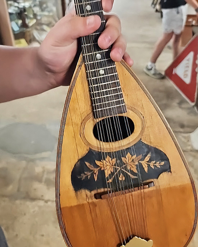 Hands cradle a vintage mandolin, its wooden body telling tales of front porch serenades and musical evenings long before digital streaming.
