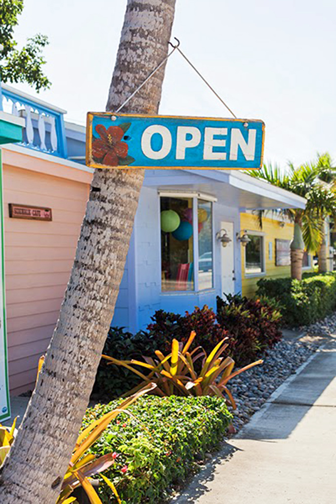 The happiest sign in the Keys! This weathered "OPEN" placard hanging from a palm tree signals good things await inside the colorful building.