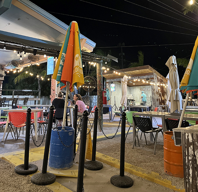 As twilight descends, the outdoor dining area transforms into a magical space where colorful umbrellas stand guard over tables of happy diners.