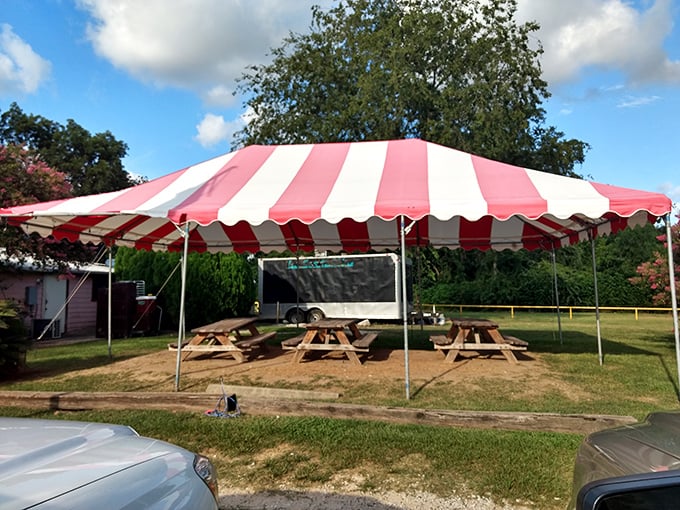 The outdoor seating area, complete with cheerful red-and-white tent, offers a perfect spot for summer gatherings and Texas-sized appetites.
