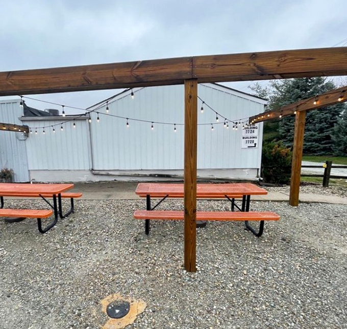 Outdoor seating where string lights transform simple picnic tables into an al fresco barbecue paradise. Even the gravel looks happy to be there.