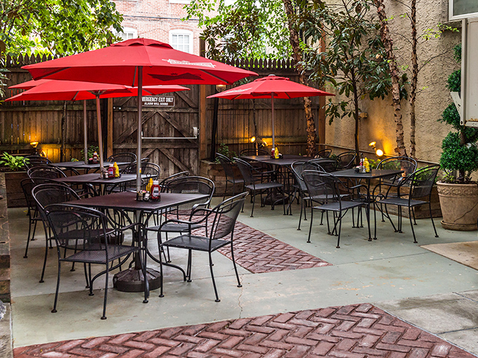 The outdoor patio where summer evenings stretch into night, red umbrellas standing guard over countless happy hour revelations.