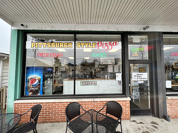 The front window proudly announces "Pittsburgh Style Pizza" in neon. Those outdoor tables aren't just furniture—they're front-row seats to pizza anticipation.