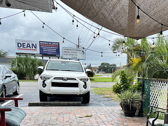 Even the parking lot has personality. Palm trees stand guard while string lights overhead promise that good times await just beyond that vibrant blue facade.