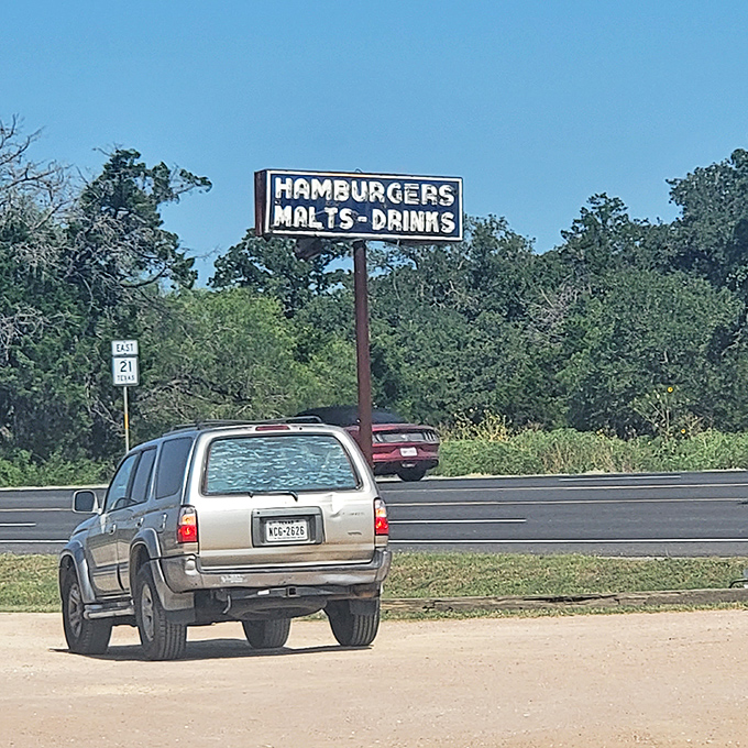 That vintage roadside sign promising "HAMBURGERS MALTS-DRINKS" is the kind of honest advertising Madison Avenue could learn something from.
