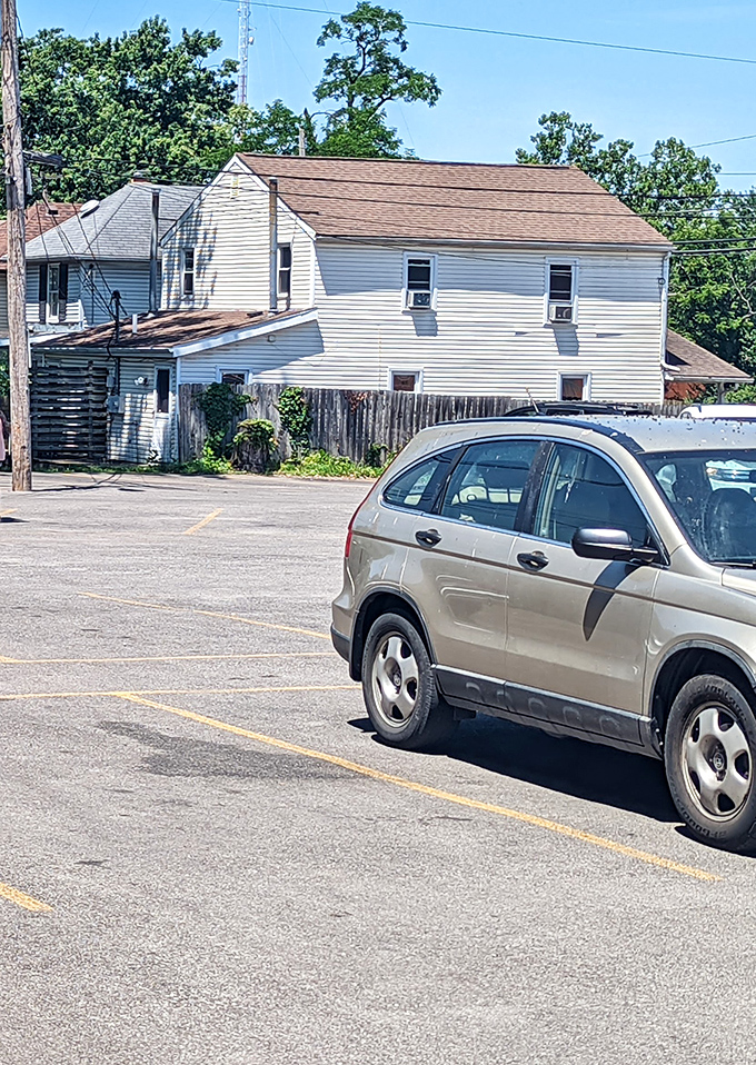 The unassuming parking lot—where vehicles wait patiently while their owners experience meat euphoria inside.