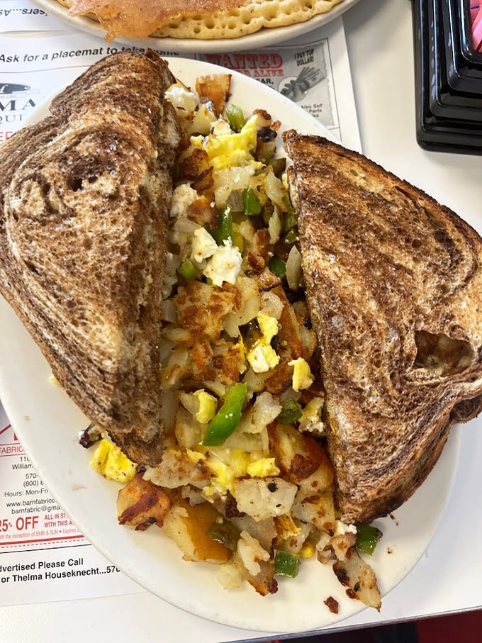 Breakfast engineering at its finest: Crispy toast barely containing a mountain of perfectly seasoned potatoes, eggs, and peppers.