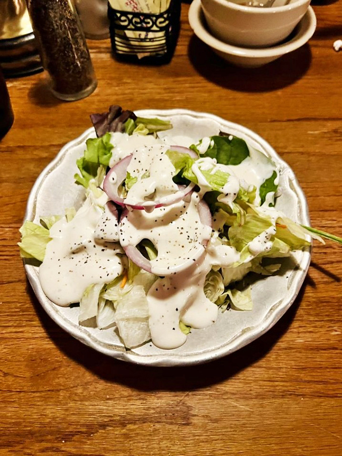 A house salad that doesn't pretend to be the main event but still shows up dressed appropriately with crisp vegetables and creamy dressing.