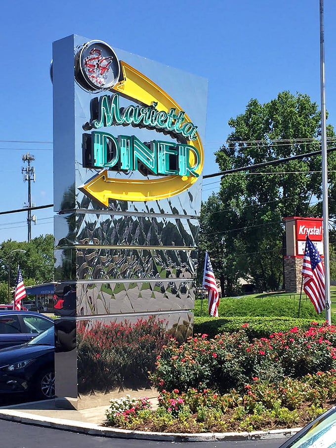 The roadside sign stands tall and proud, a chrome-clad sentinel announcing to hungry travelers that paradise is just one exit away.
