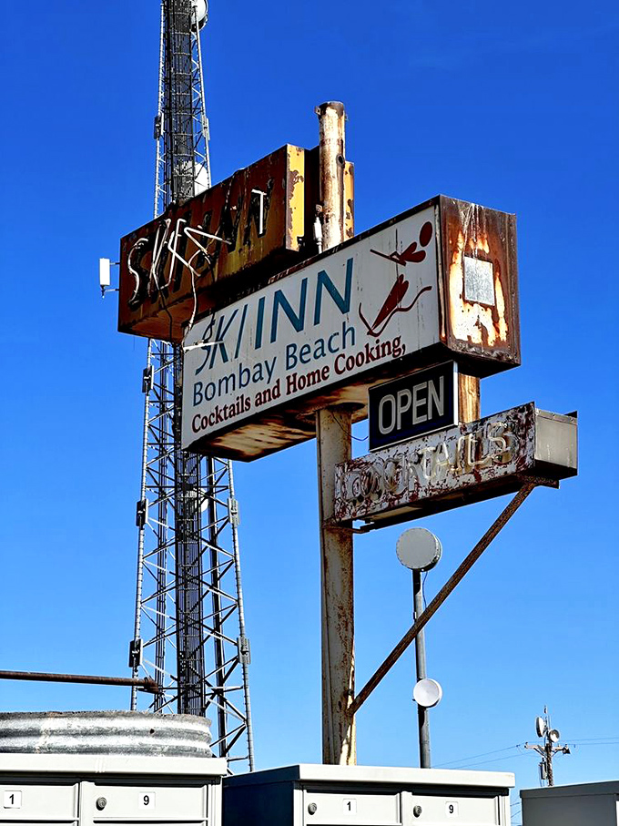 The weathered sign stands like a sentinel against the desert sky, promising "Cocktails and Home Cooking" to weary travelers.