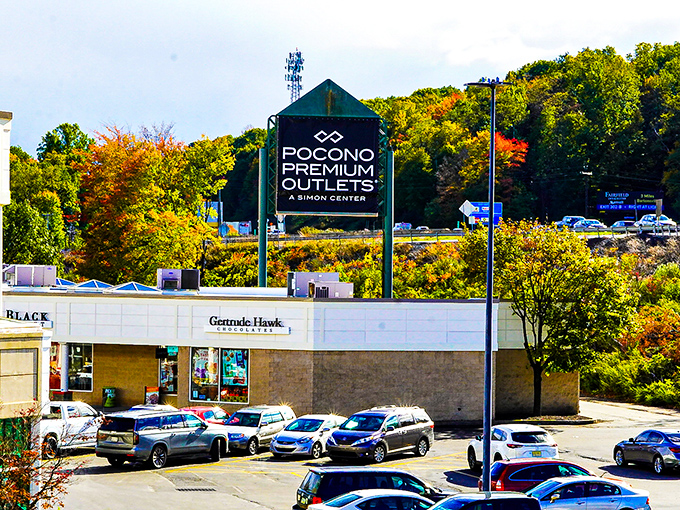 Fall foliage frames the Pocono Premium Outlets sign, creating a scene where nature's beauty competes with manufactured bargains for your attention.