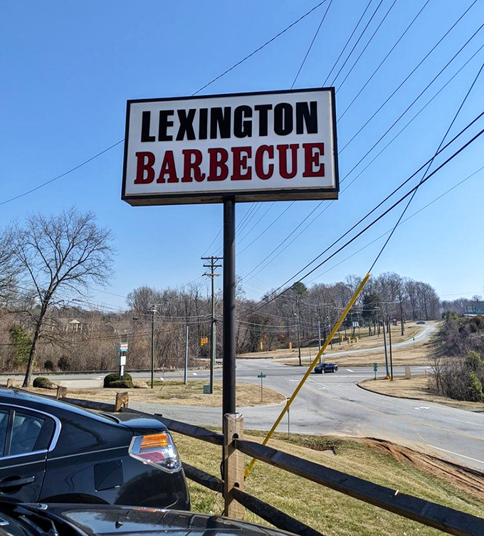The sign stands like a beacon of barbecue hope against the Carolina blue sky. No fancy graphics needed when your reputation speaks this loudly.