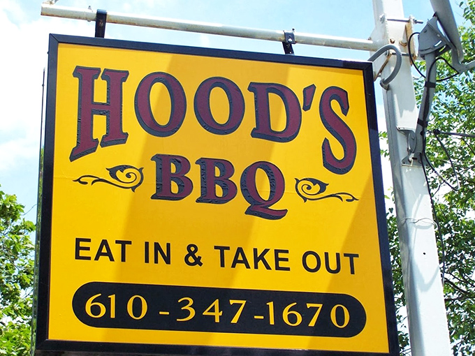 The bright yellow sign that acts like a barbecue lighthouse, guiding hungry travelers to smoky salvation just off the main road.