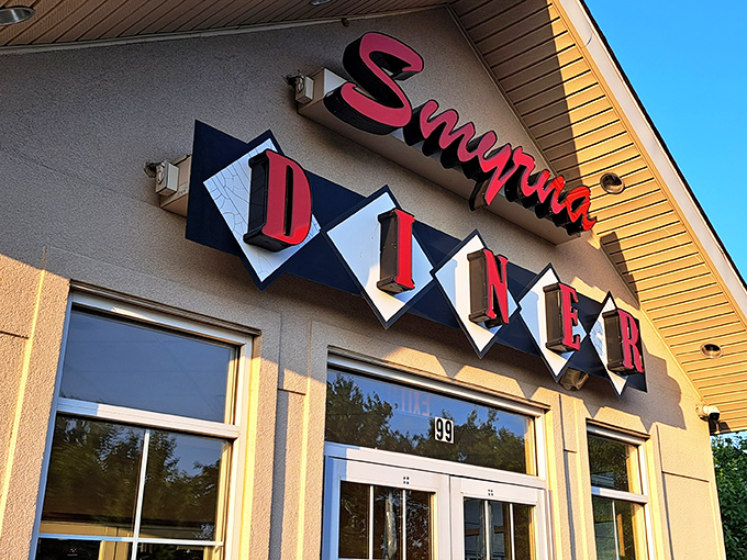 The Smyrna Diner sign glows like a neon promise against the evening sky. Some restaurants have signs; this one has a beacon.