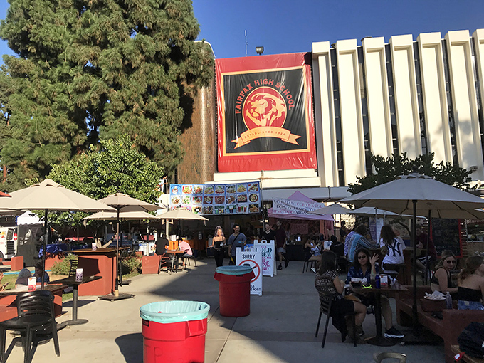 The food court area offers respite for weary shoppers, where Fairfax High School's banner reminds you that your purchases support education.