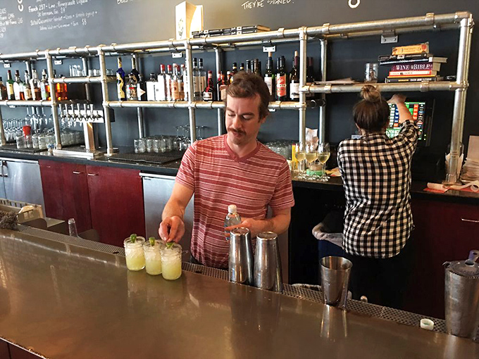 The bartender crafts liquid magic while diners contemplate their next delicious decision at the bar.