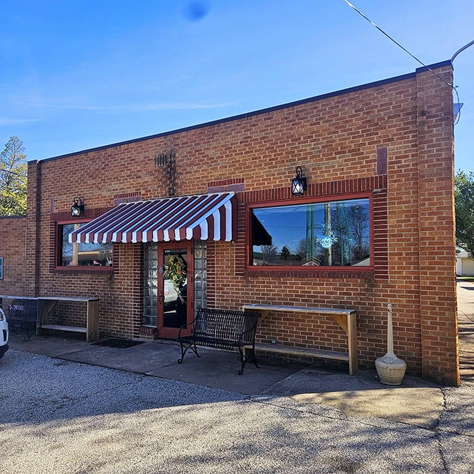 Morning light catches the brick storefront, where a simple bench invites you to sit a spell. No pretension, just the promise of honest food inside.