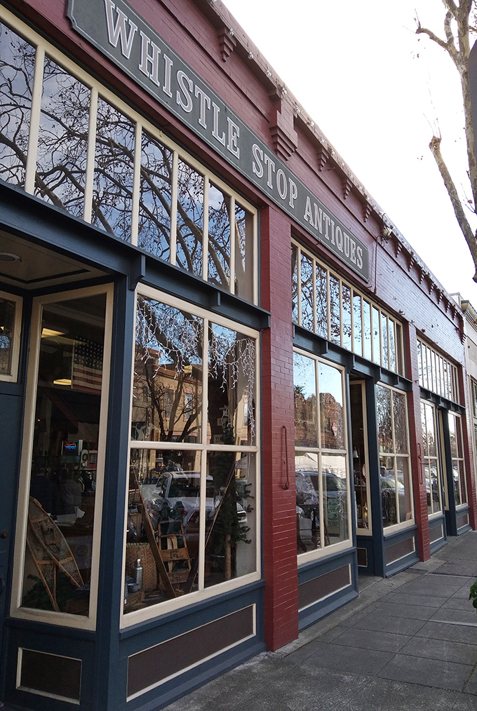Large storefront windows frame the entrance to Whistlestop Antiques, inviting passersby to step into a world of vintage treasures.