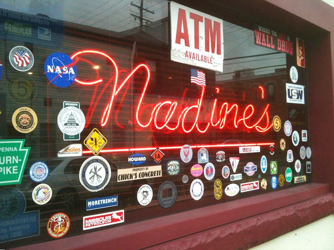 The window sign collection tells stories of Pittsburgh pride, with the neon "Nadine's" glowing like a beacon for hungry travelers.