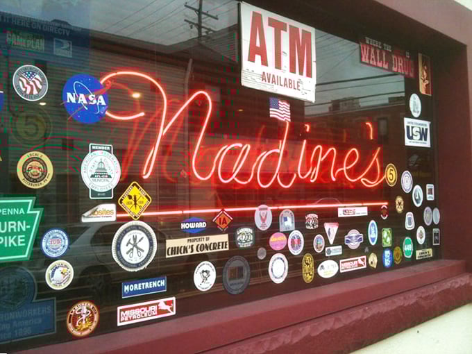 The window sign collection tells stories of Pittsburgh pride, with the neon "Nadine's" glowing like a beacon for hungry travelers.