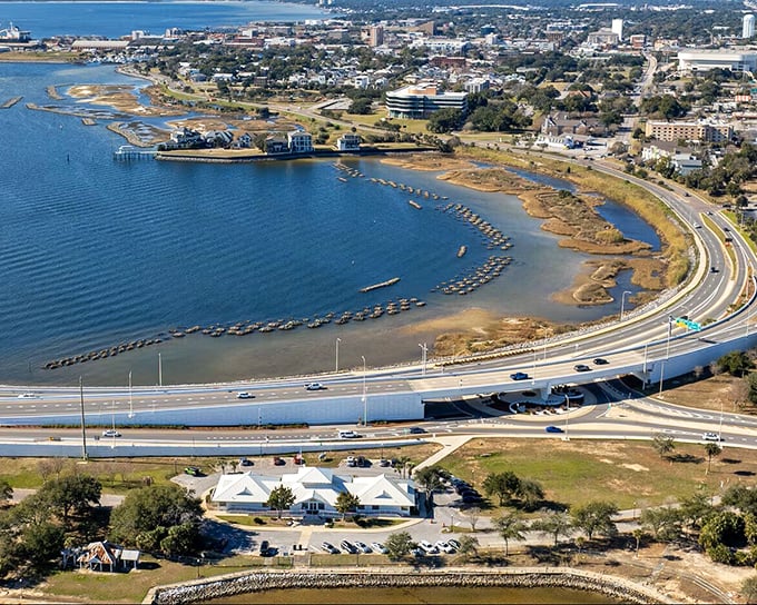 The view from above reveals Pensacola's waterfront beauty, where coastal highways curve alongside azure waters.