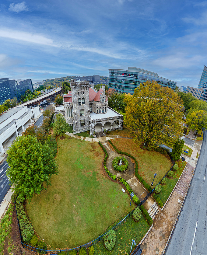 From above, Rhodes Hall's distinctive red roof and stone tower create a striking contrast with modern Atlanta. A historic island in a sea of progress.