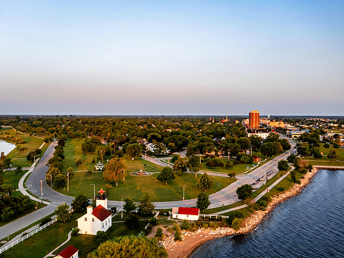 From above, Escanaba reveals its perfect positioning between green parkland and blue waters, with the lighthouse standing guard at the edge.
