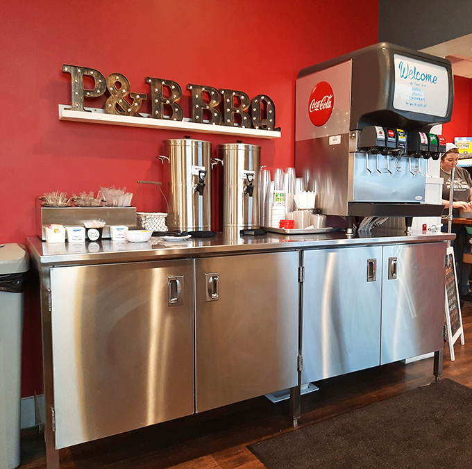 The drink station—where sweet tea flows like liquid sunshine and the illuminated P&B BBQ sign reminds you exactly where barbecue heaven is located.