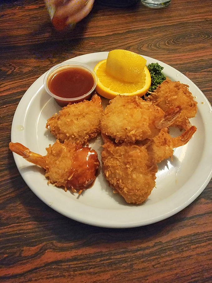 Coconut shrimp dressed for success with a vibrant orange slice. The golden coating crackles with each bite, revealing sweet treasures within.