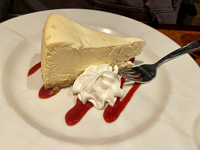 A slice of cheesecake so creamy it should be illegal, with just enough raspberry sauce to make your taste buds sing.