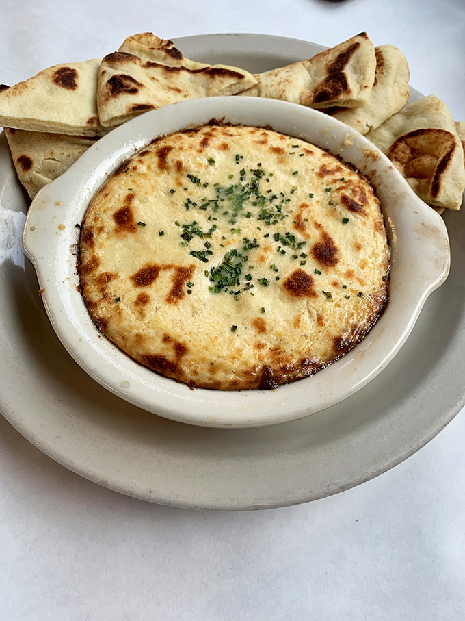 Bubbling hot crab dip with a golden-brown crust and warm pita triangles. Sharing is technically optional but not recommended for maximum enjoyment.