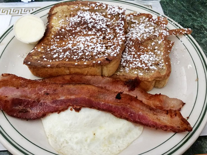 French toast dusted with powdered sugar like a light Pennsylvania snowfall, accompanied by crispy bacon and a perfectly cooked egg. The breakfast holy trinity.